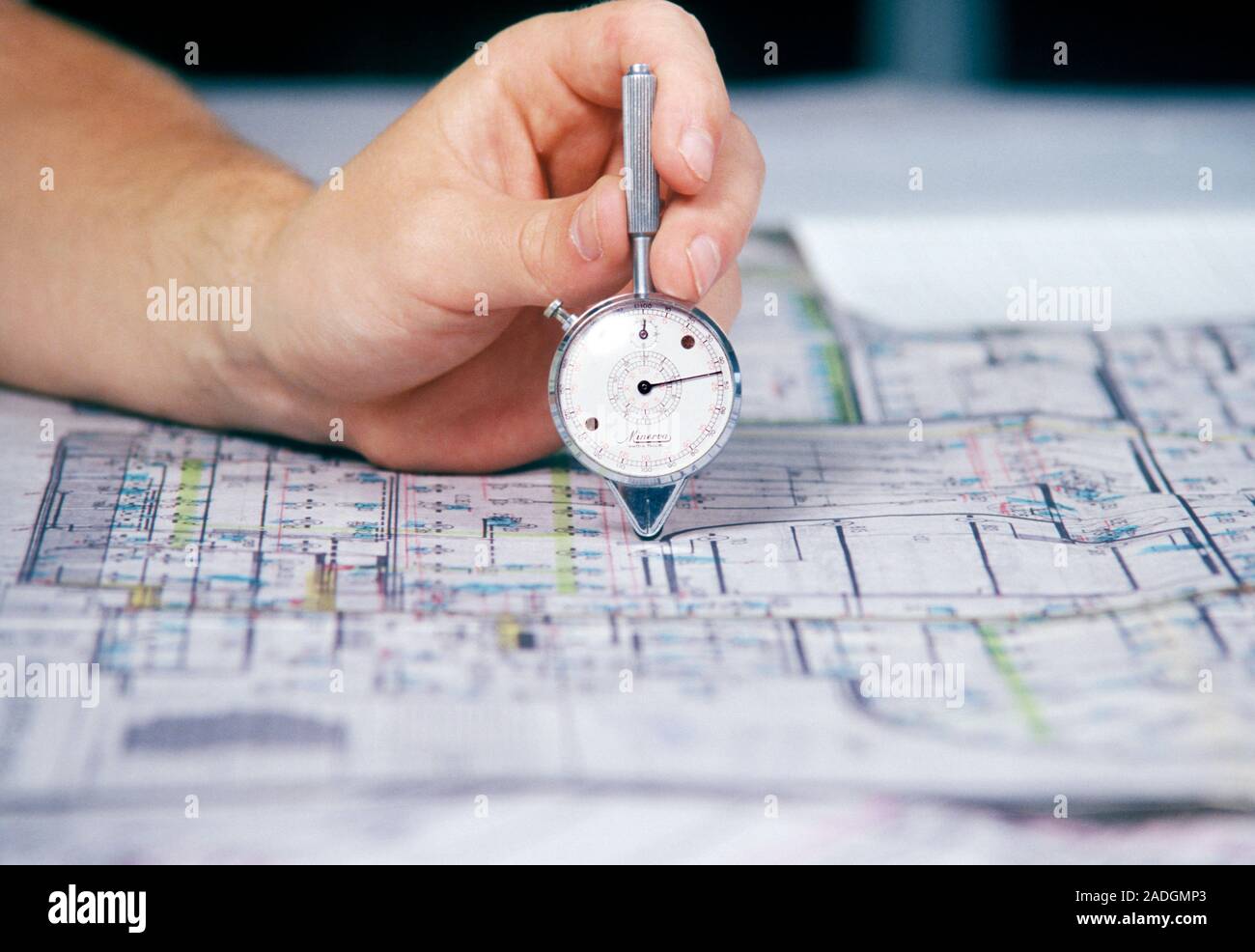 Map wheel. Engineer using a map wheel to measure distance on a plan ...