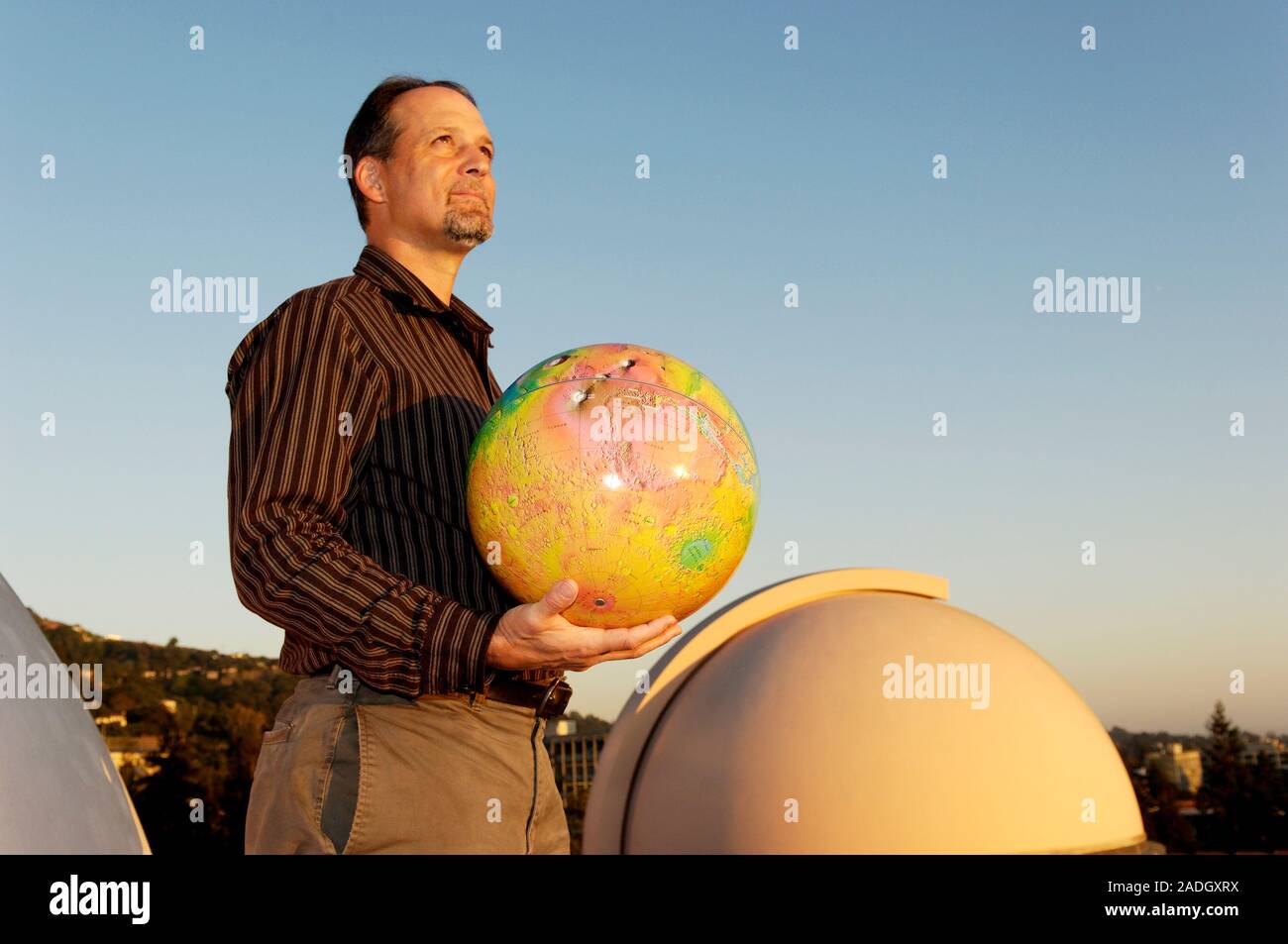 Professor Geoffrey Marcy, astrophysicist, holding a globe of the planet ...