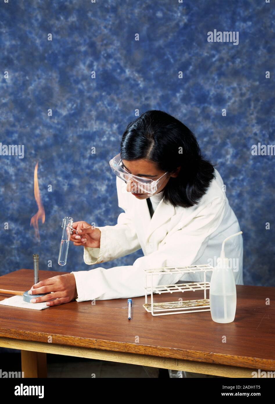 Chemistry student adjusting a Bunsen burner flame during a school ...