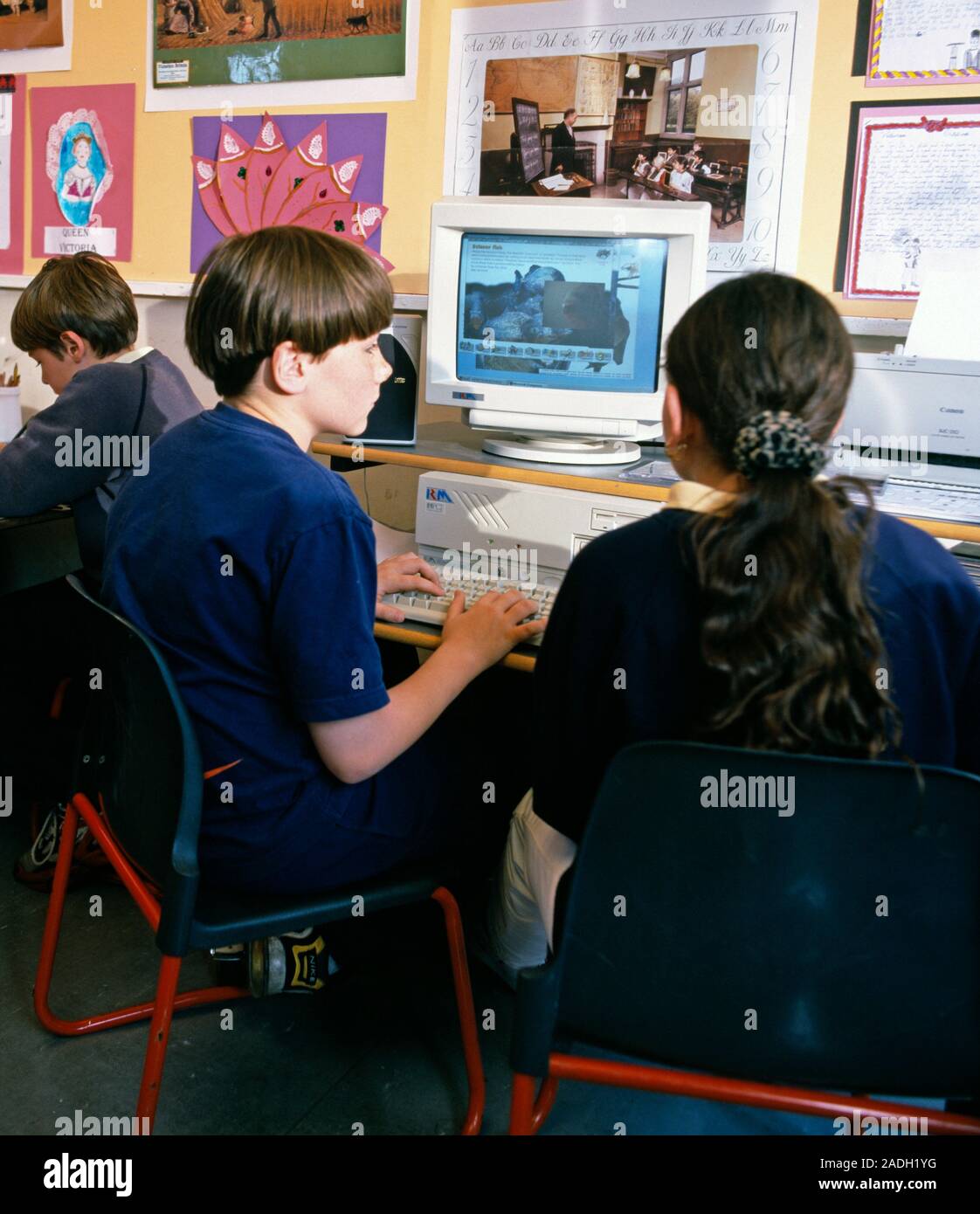 Schoolchildren working at a computer in school Stock Photo - Alamy