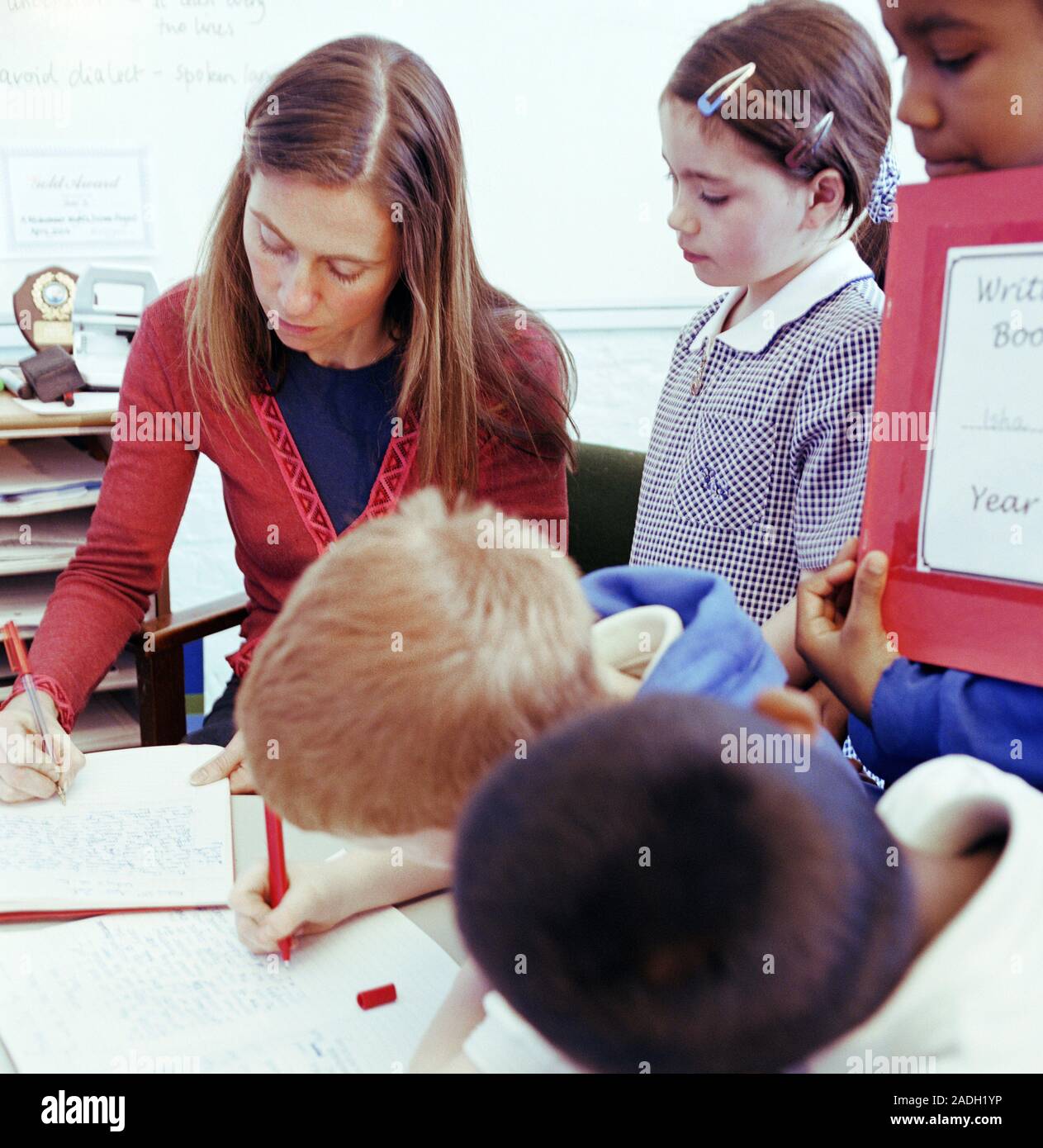 Teacher marking work during a writing lesson Stock Photo - Alamy