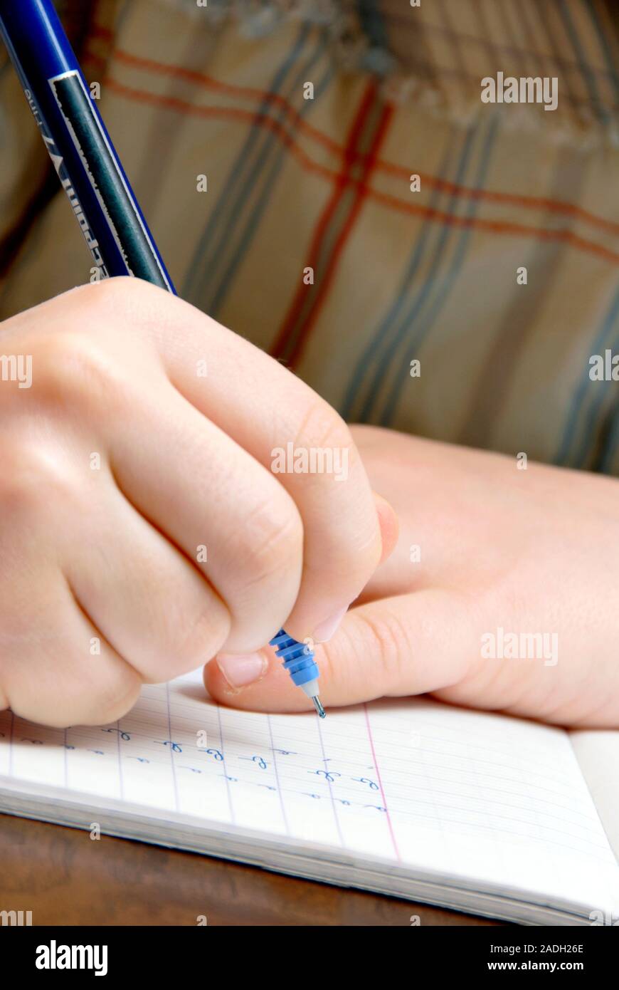 MODEL RELEASED. Handwriting practice. Boy writing in an exercise book ...