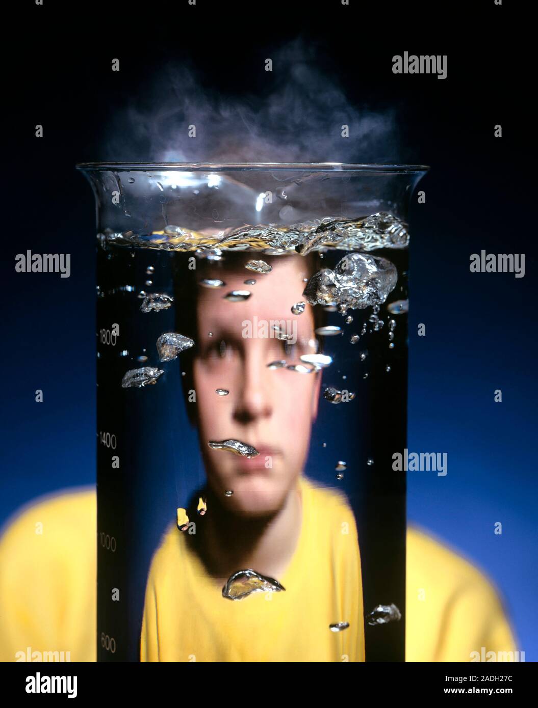 Science experiment. Schoolboy watching water boil in a beaker as part ...