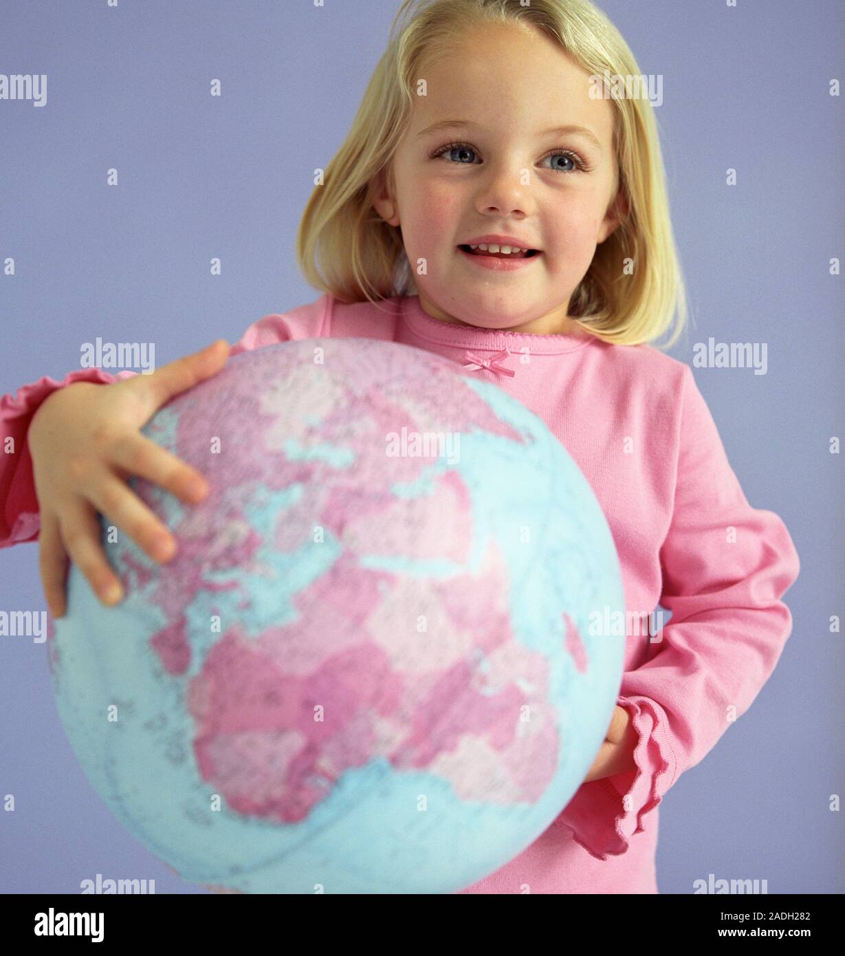 Learning geography. 3-year-old girl holding an inflated globe showing a ...