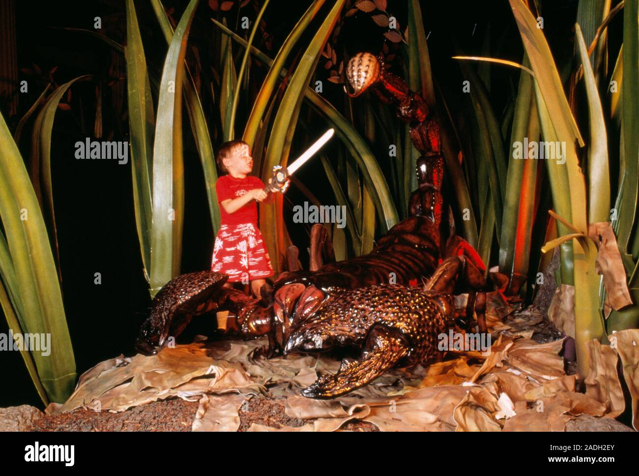Model scorpion. Young child holding a sword, interacting with a giant ...