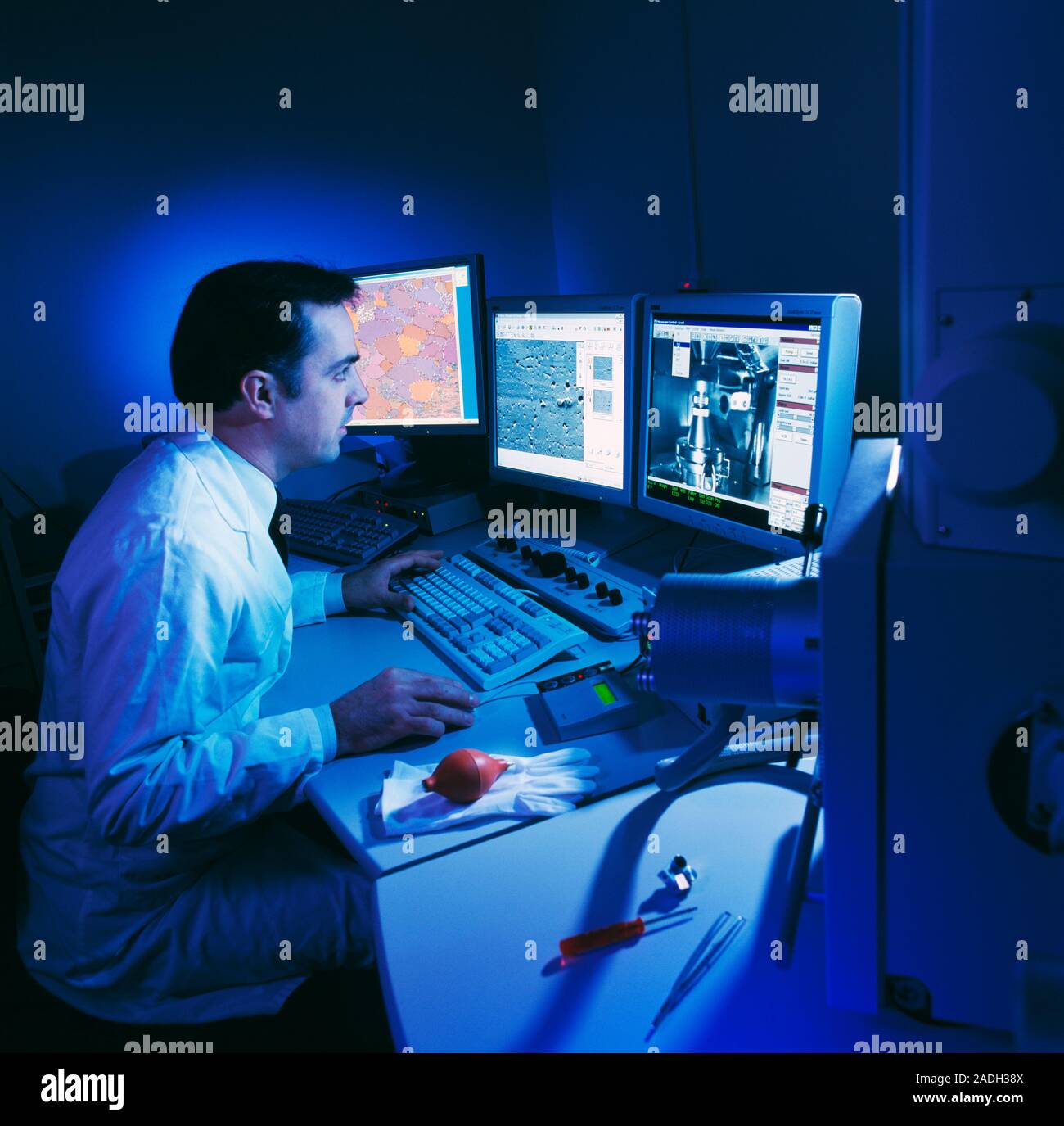 MODEL RELEASED. Scanning electron microscope. Scientist positioning a ...