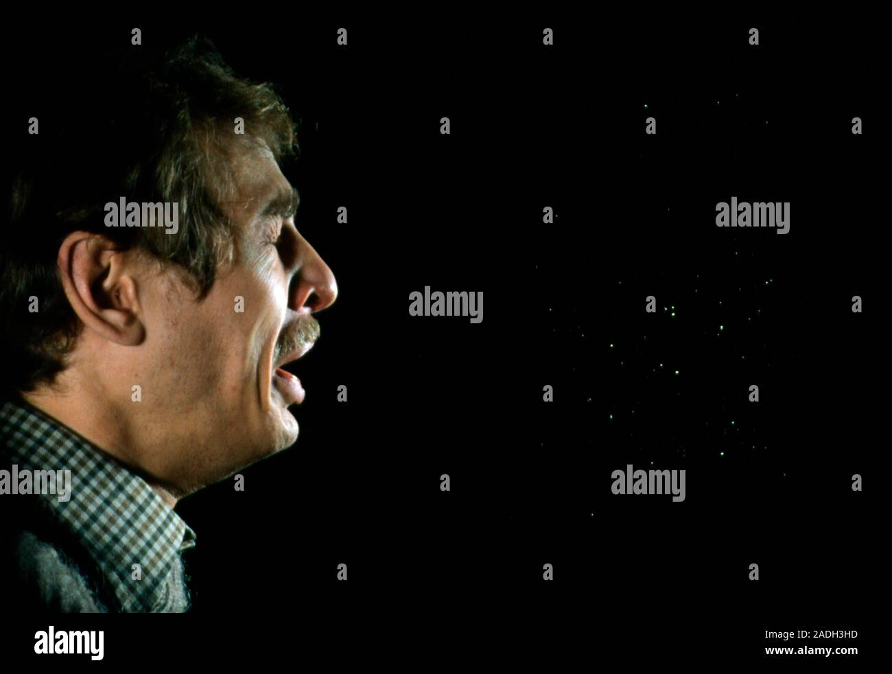 High-speed photograph of a man sneezing, showing droplets of water ...