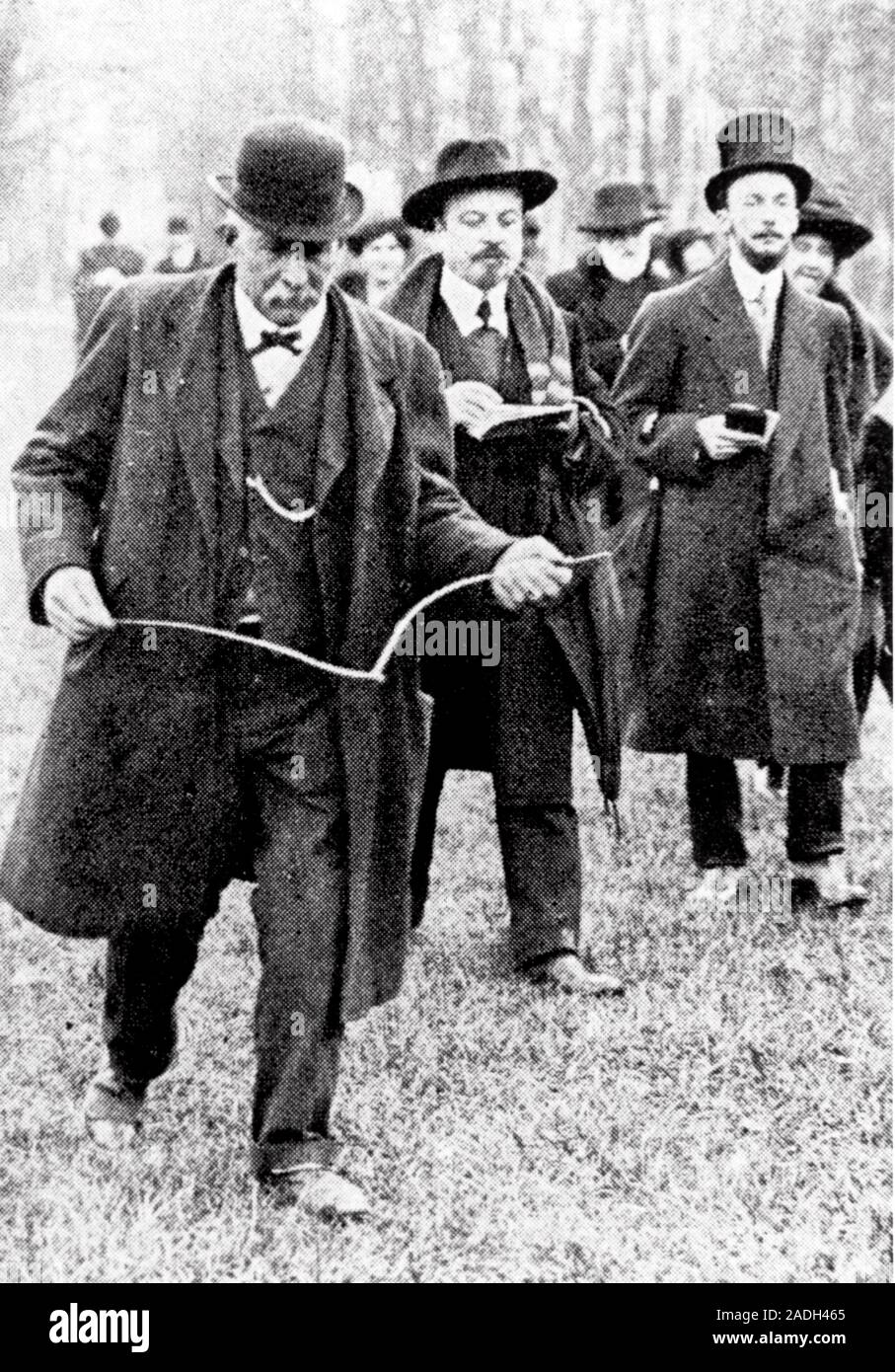 Dowsing. Man using a forked rod whilst divining for underground water ...