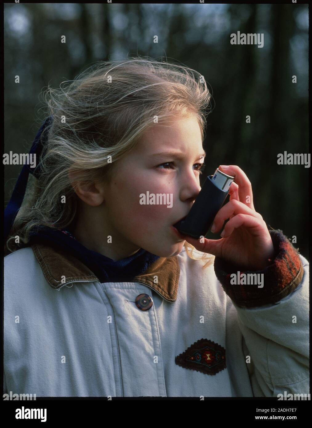 Aerosol inhaler for asthma. Young girl using an aerosol inhaler for the ...