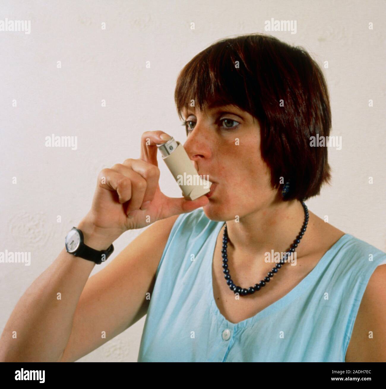 Woman using a Becotide aerosol inhaler to control attacks of bronchial ...