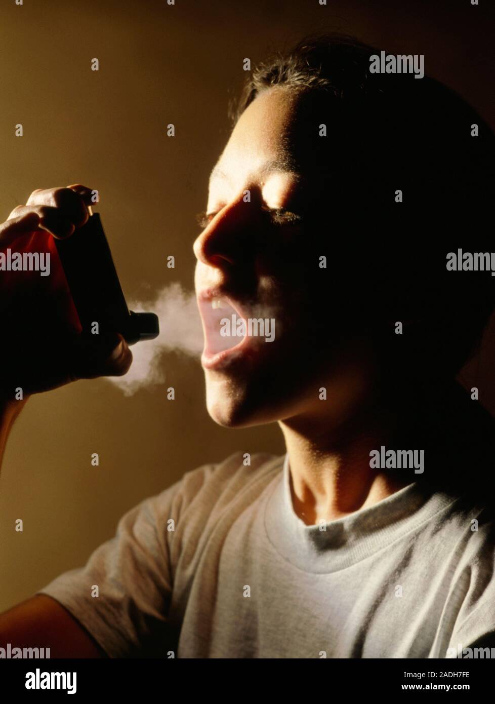 Inhaler for asthma. Young woman using an aerosol inhaler for the ...