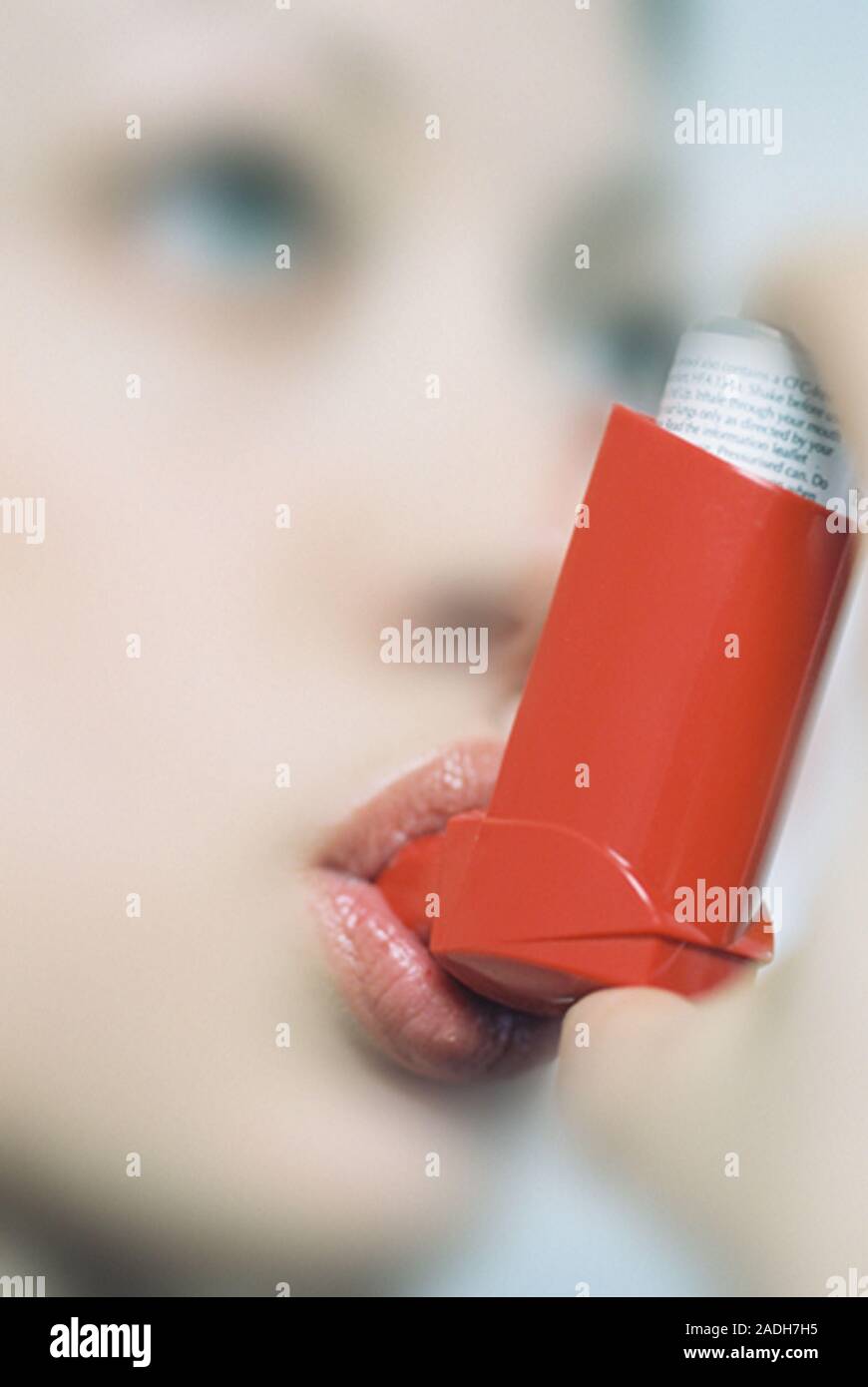 Asthma inhaler. Woman using an aerosol inhaler for the treatment of ...