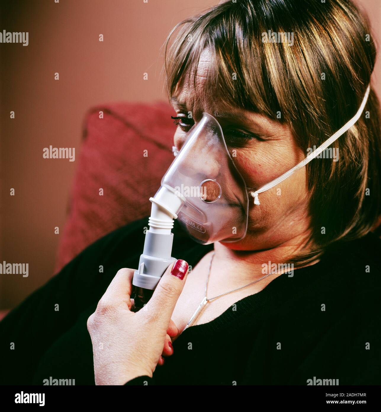 MODEL RELEASED. Nebulizer use. Woman using a nebulizer at home Stock ...