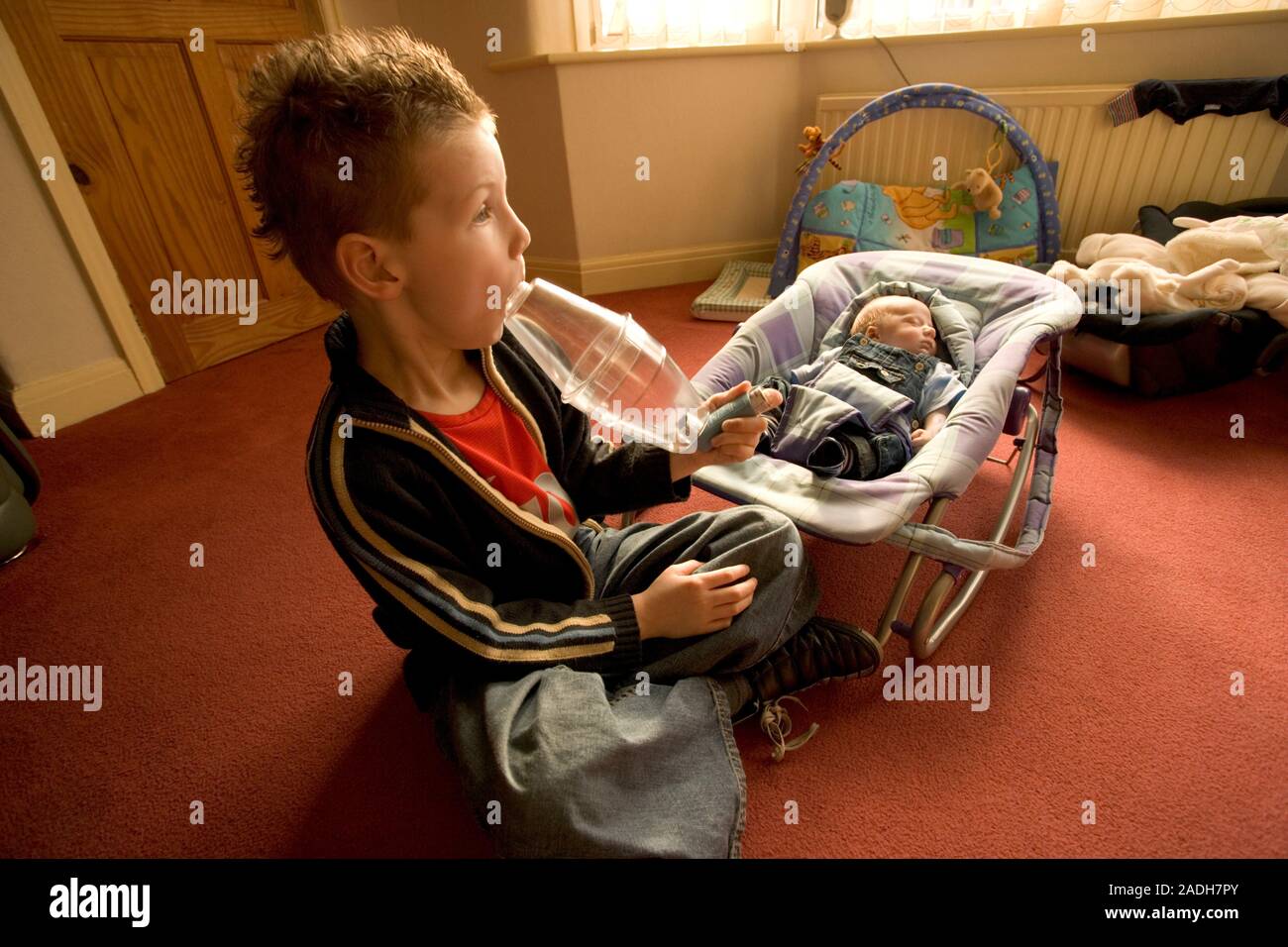Asthma inhaler use. Young boy using a blue inhaler to treat an asthma ...