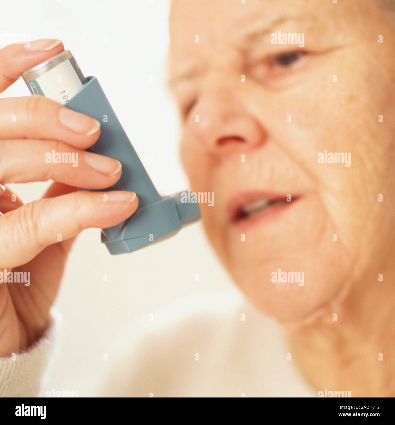 Woman using an inhaler to treat an asthma attack. The inhaler contains ...