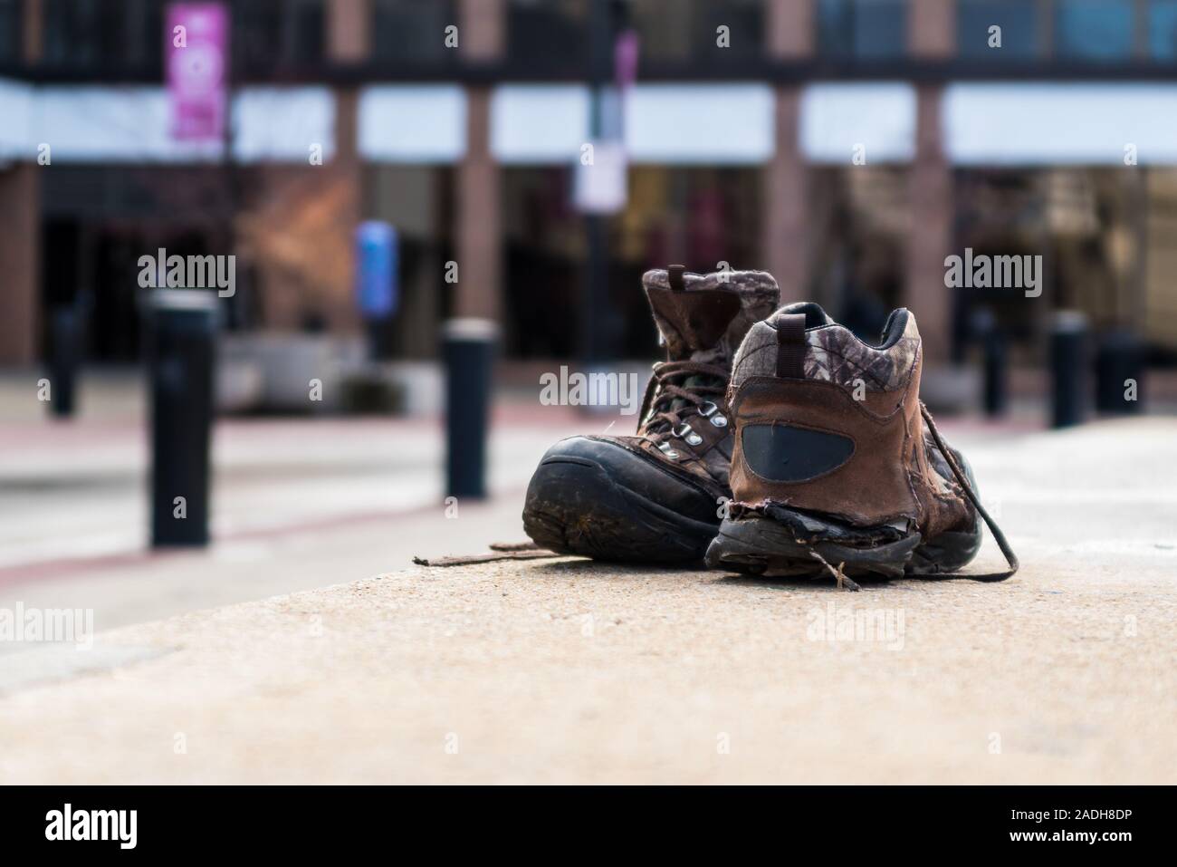 A portrait layout of a pair of old worn out work boots shoes sitting on ...