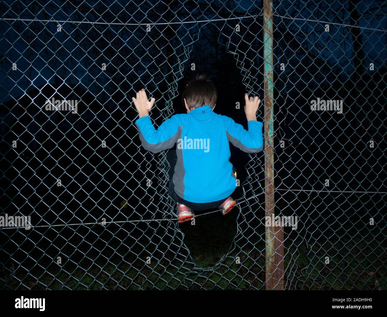 Boy Escaping Through Fence Stock Photo - Alamy