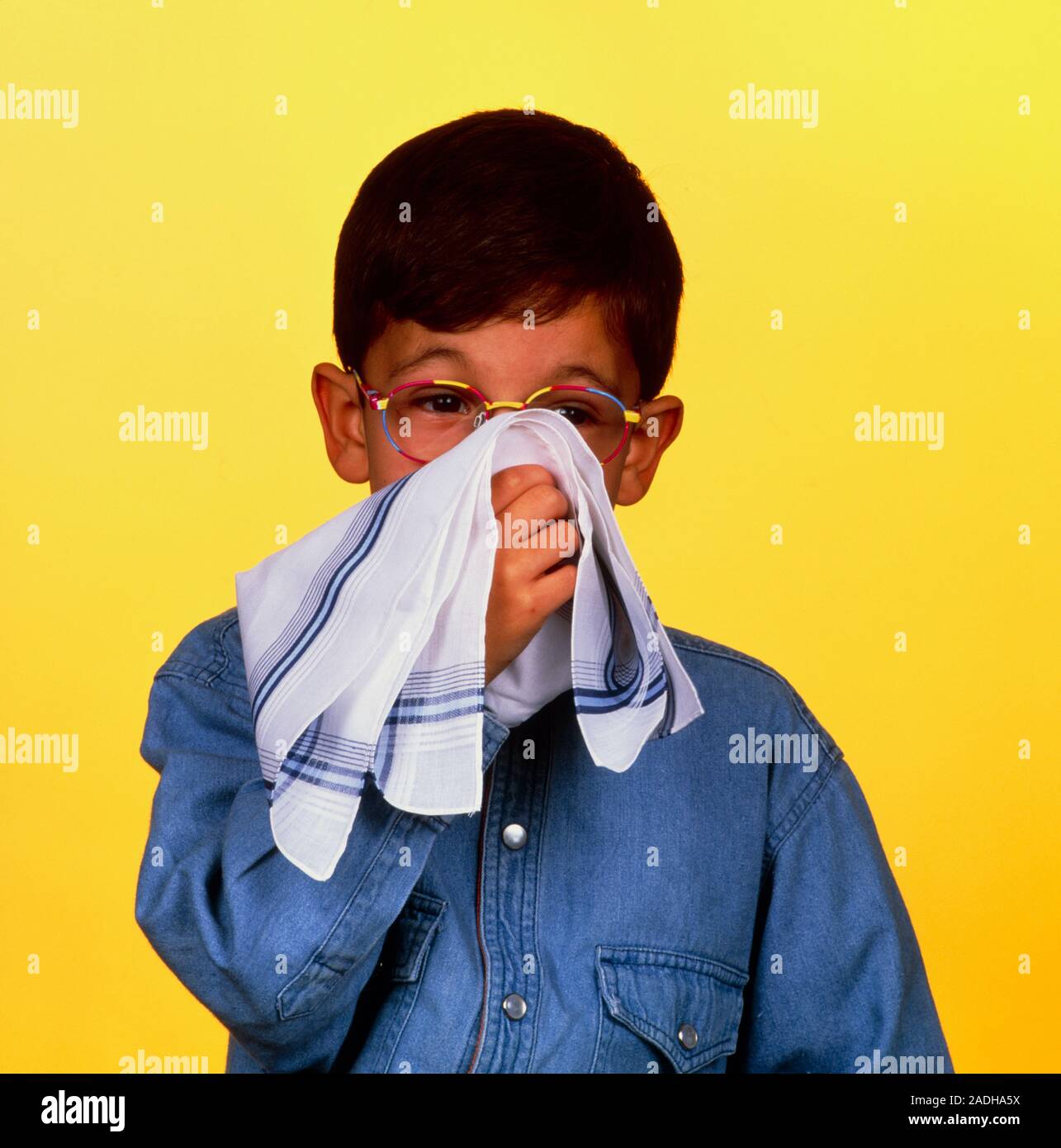 Rhinitis. Five year old boy blowing his nose with a tissue while ...