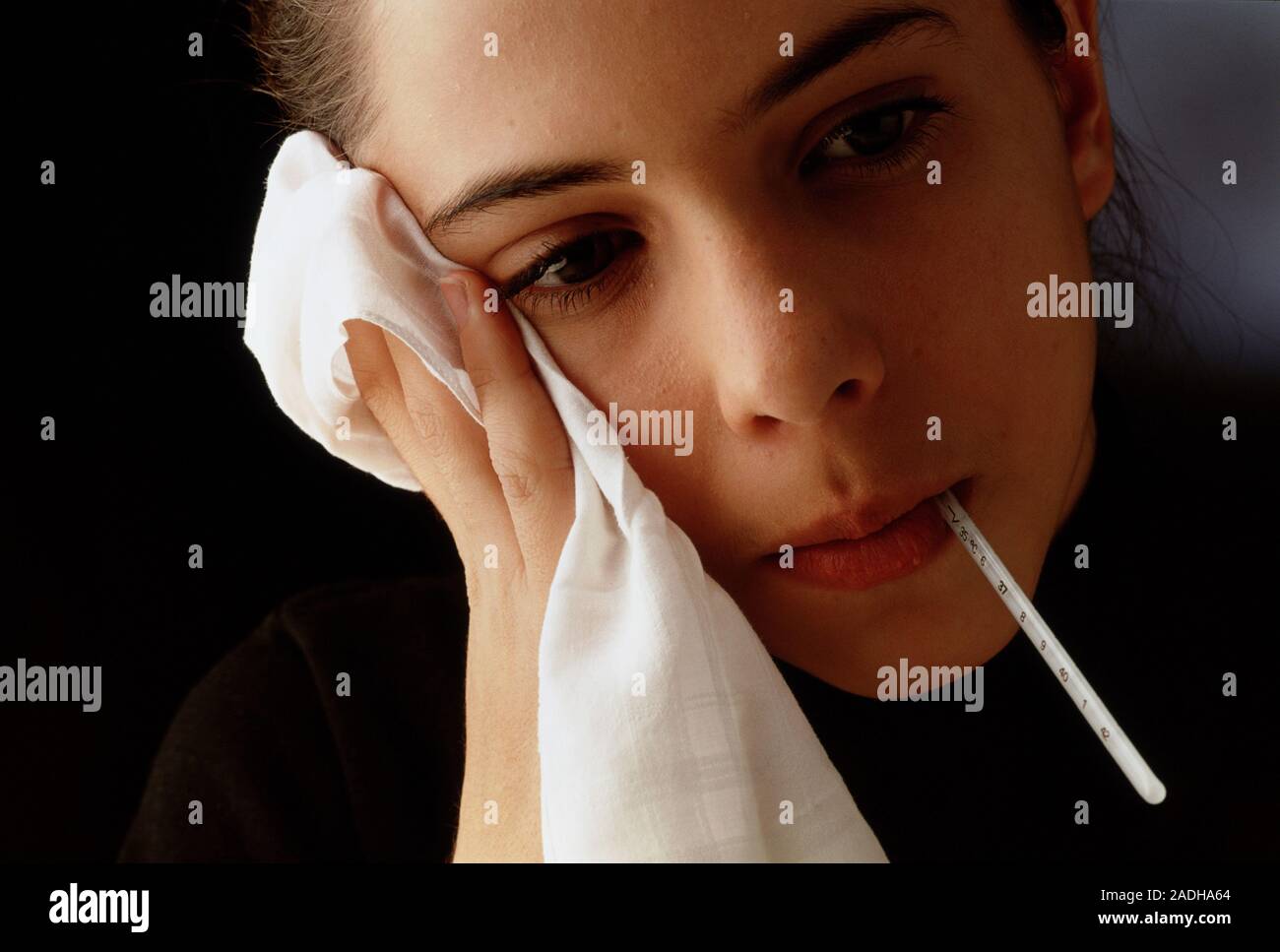 Common cold. Teenage girl suffering from a common cold checks her ...