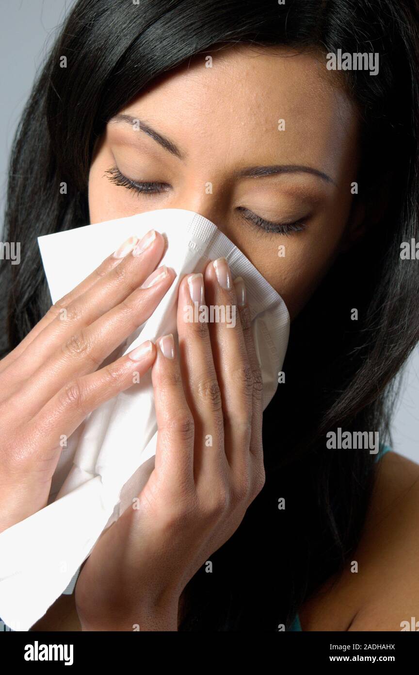 MODEL RELEASED. Blowing nose. Young woman blowing her nose. She has ...