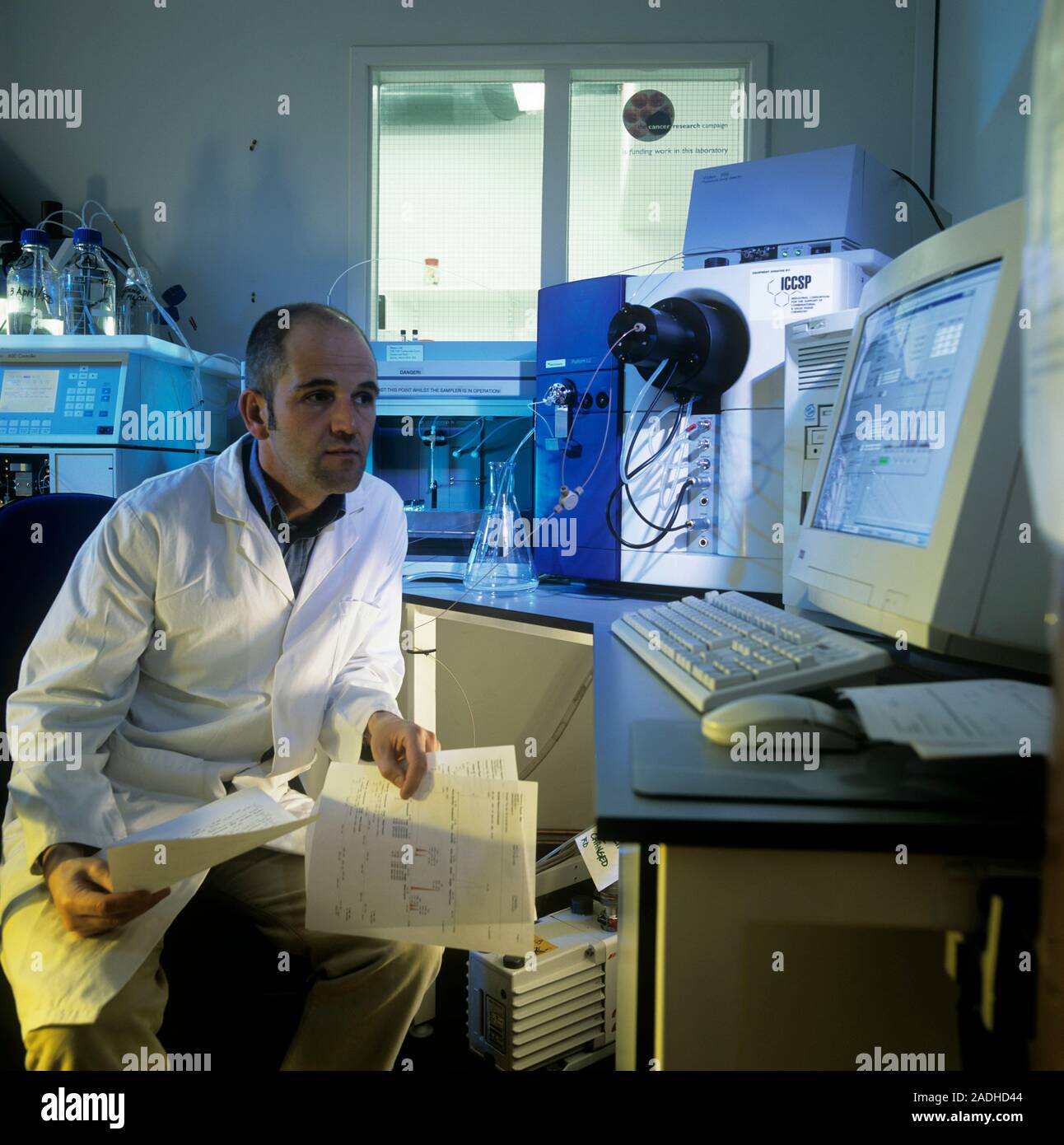 MODEL RELEASED. Cancer research. Researcher studying data from a liquid ...