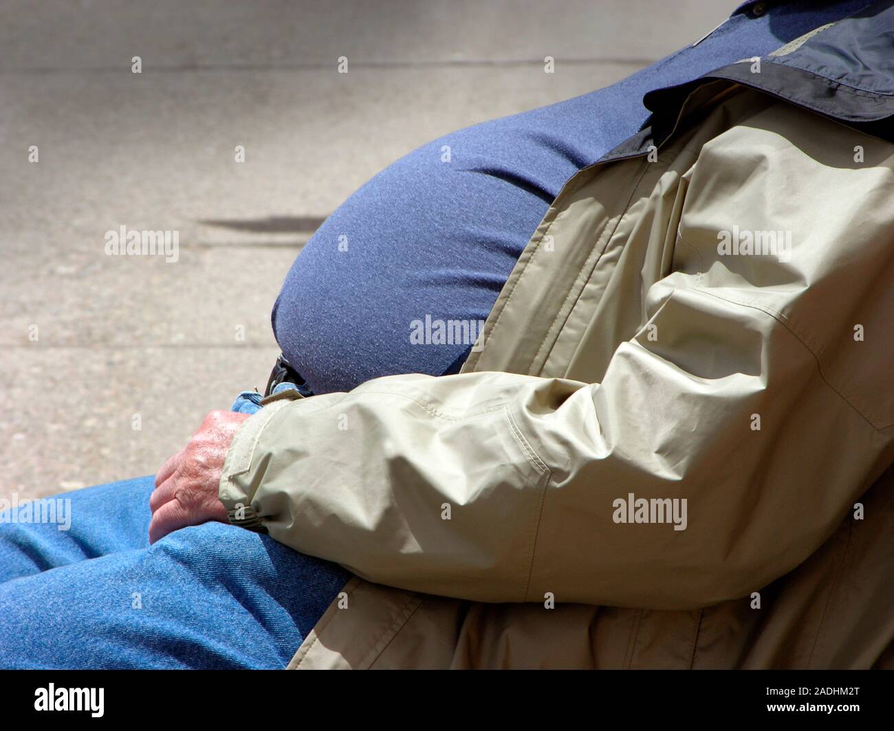 MODEL RELEASED. Overweight man sitting down outside. Photographed in ...
