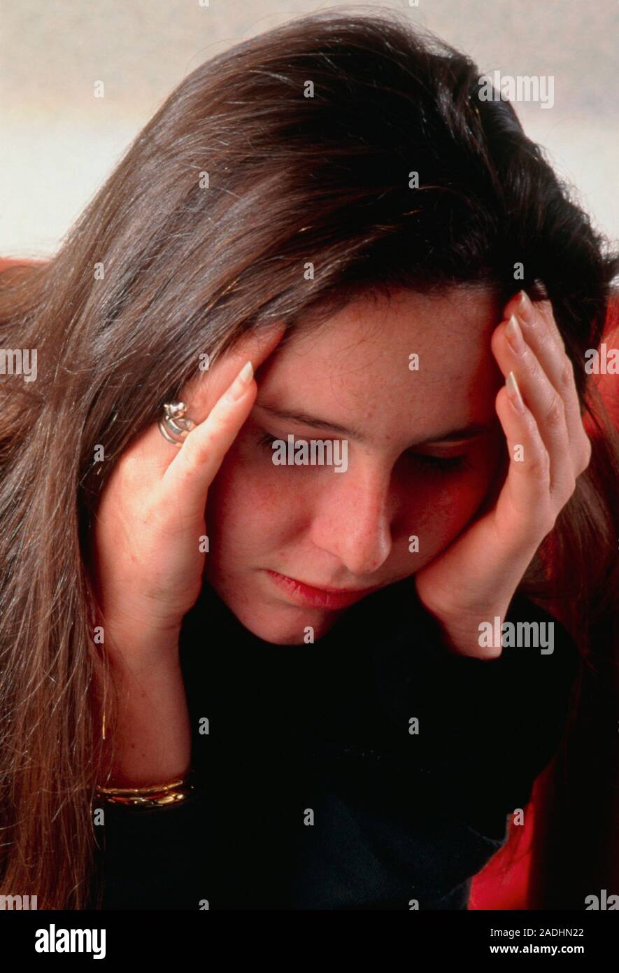 MODEL RELEASED. Depression. A young woman holds her head in her hands ...