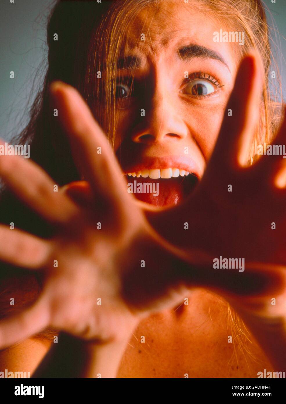 Fear or terror. Teenage girl with arms outstretched, her face ...