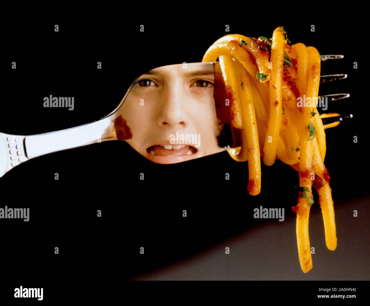 Anorexia nervosa. Girl's fearful face reflected in a fork which has a ...