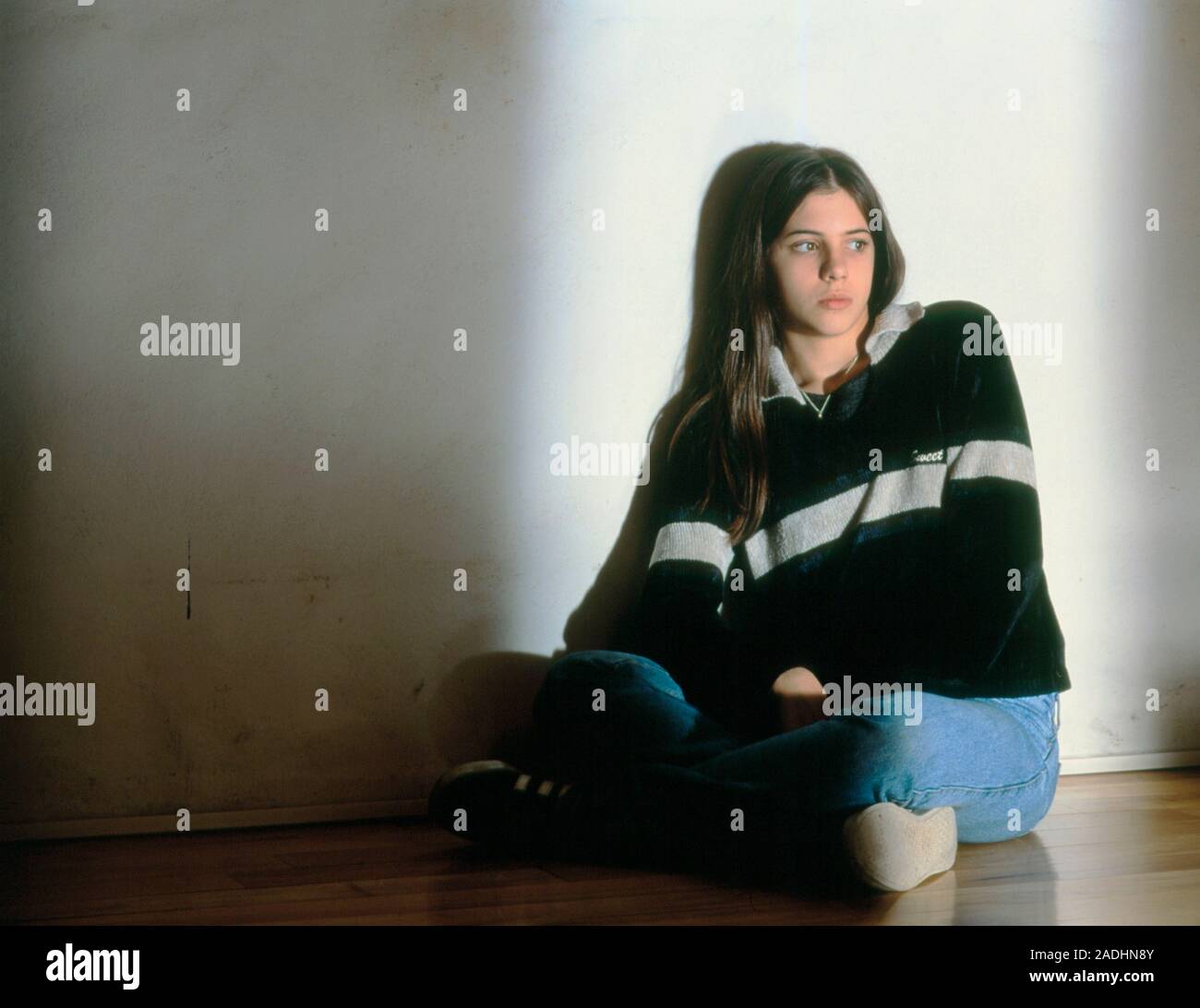 Depression. Depressed teenage girl sitting on the floor indoors. She ...