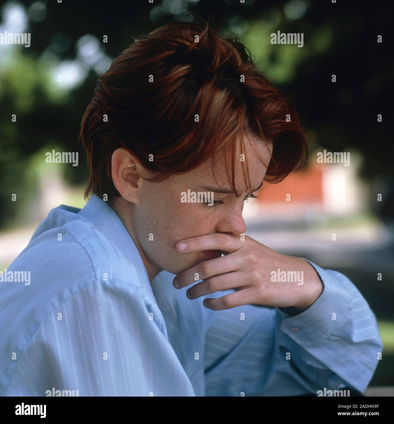 Depression. View of a teenage girl looking unhappy in a park. She may ...
