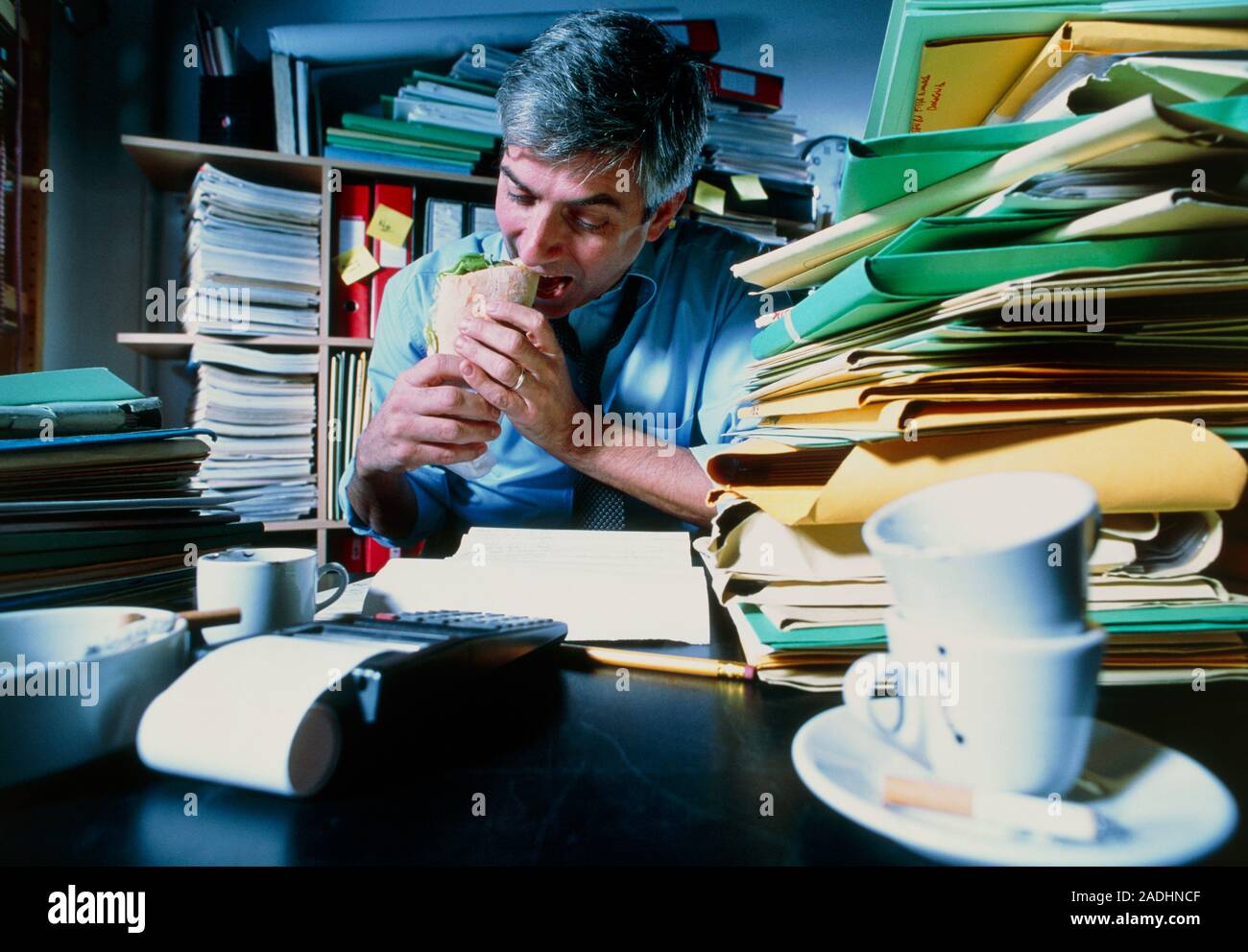 Overworked man eating a rushed lunch in his office Stock Photo - Alamy