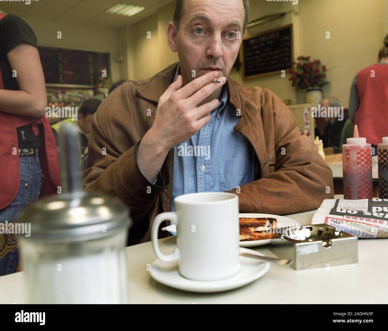 MODEL RELEASED. Depressed man smoking a cigarette in a restaurant Stock ...