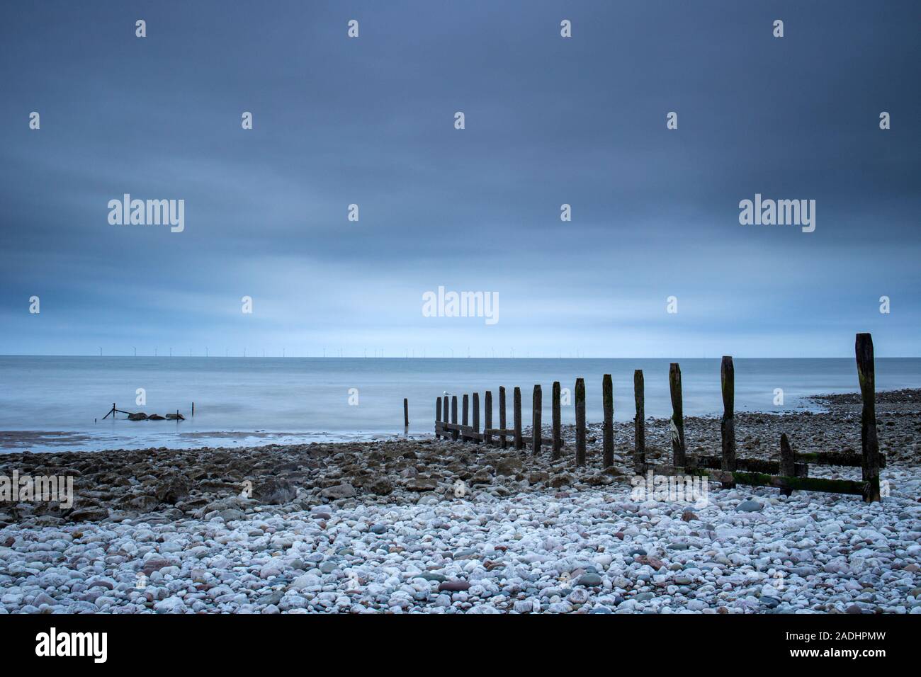 Long exposure of wooden sea defence with pebbled beach in Wales UK ...