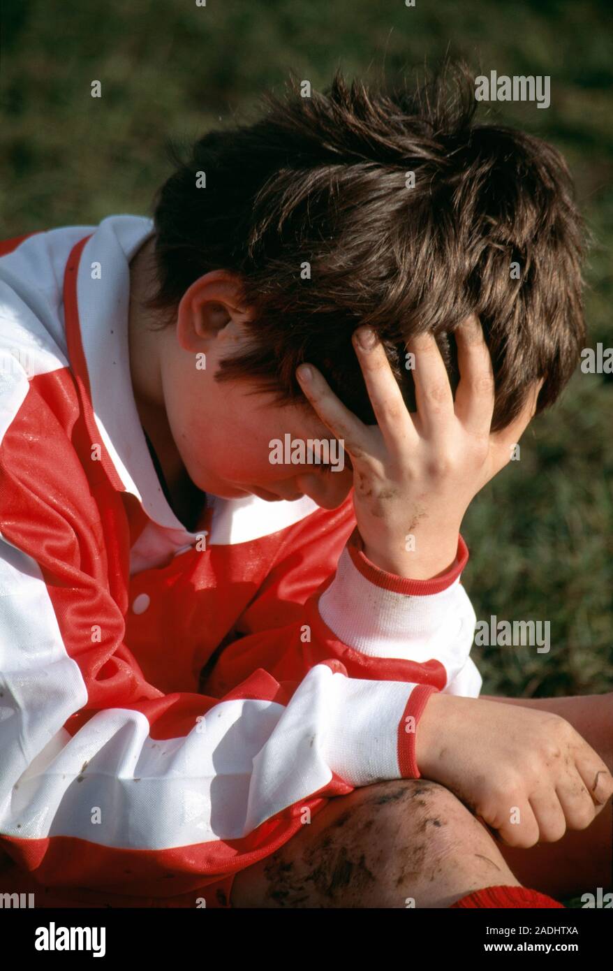 Head injury. Ten year old boy holding his head following an injury ...