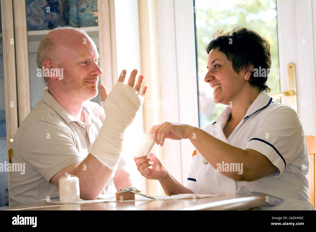MODEL RELEASED. Treatment after surgery. Nurse applying a bandage to a ...