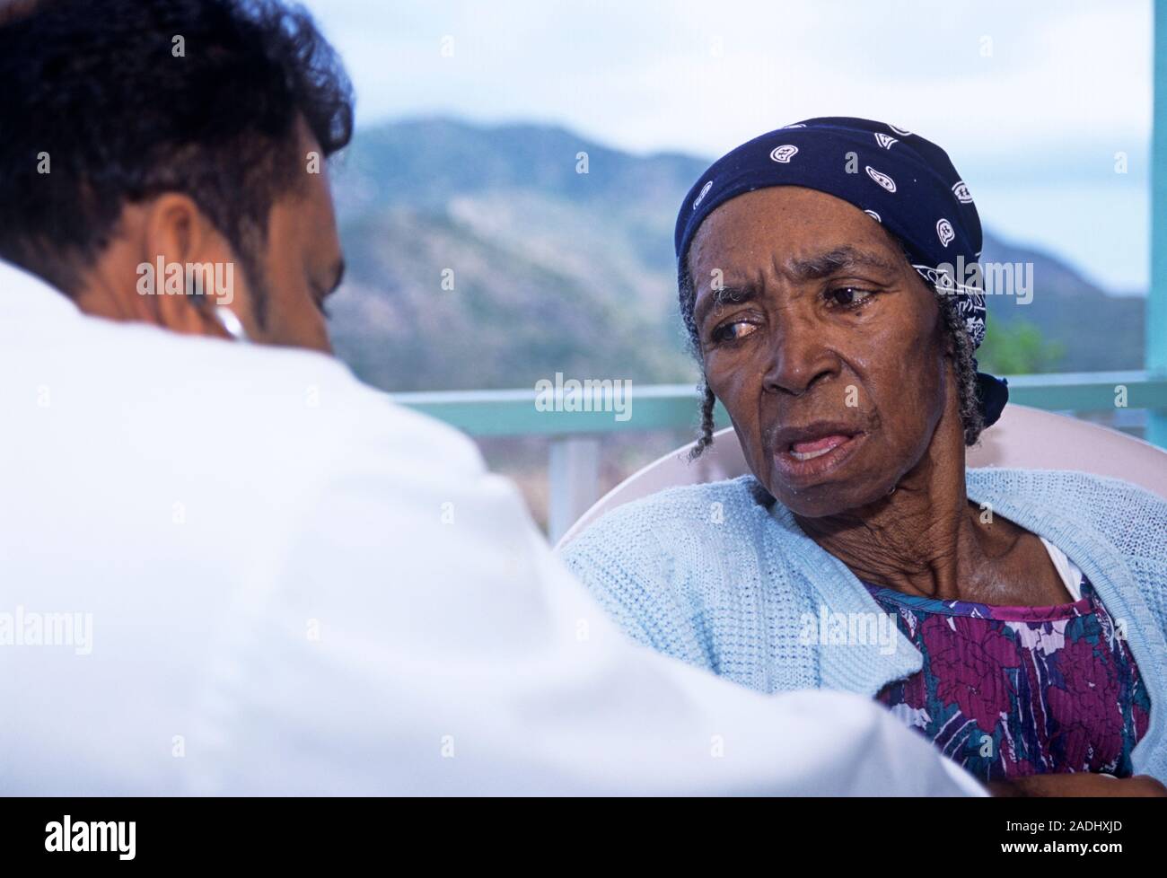 MODEL RELEASED. Geriatric care. Doctor using a stethoscope to examine ...