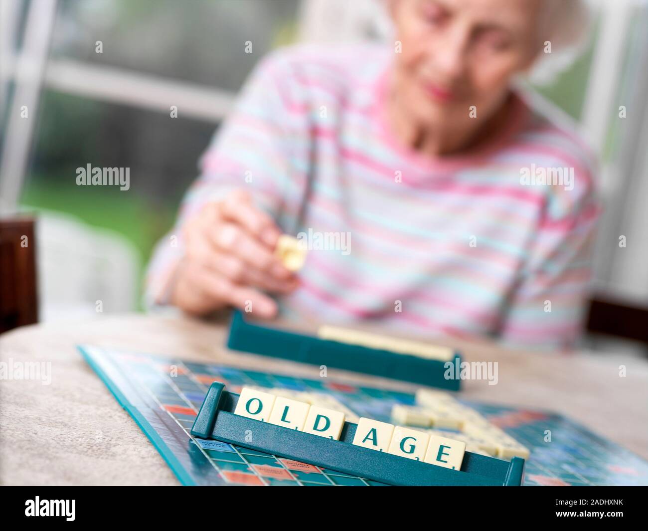 MODEL RELEASED. Geriatric care. 83 year old woman playing scrabble ...