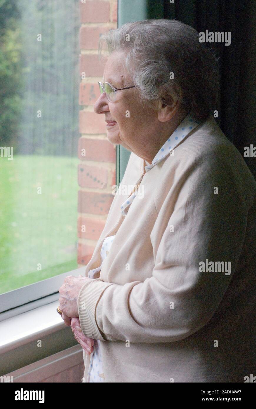 Elderly lady looking out of a window Stock Photo - Alamy