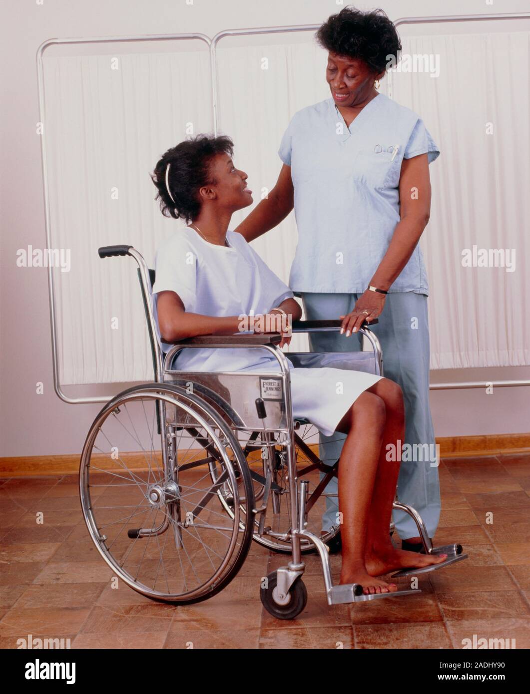 Disabled patient. A young woman confined to a wheelchair is attended to ...