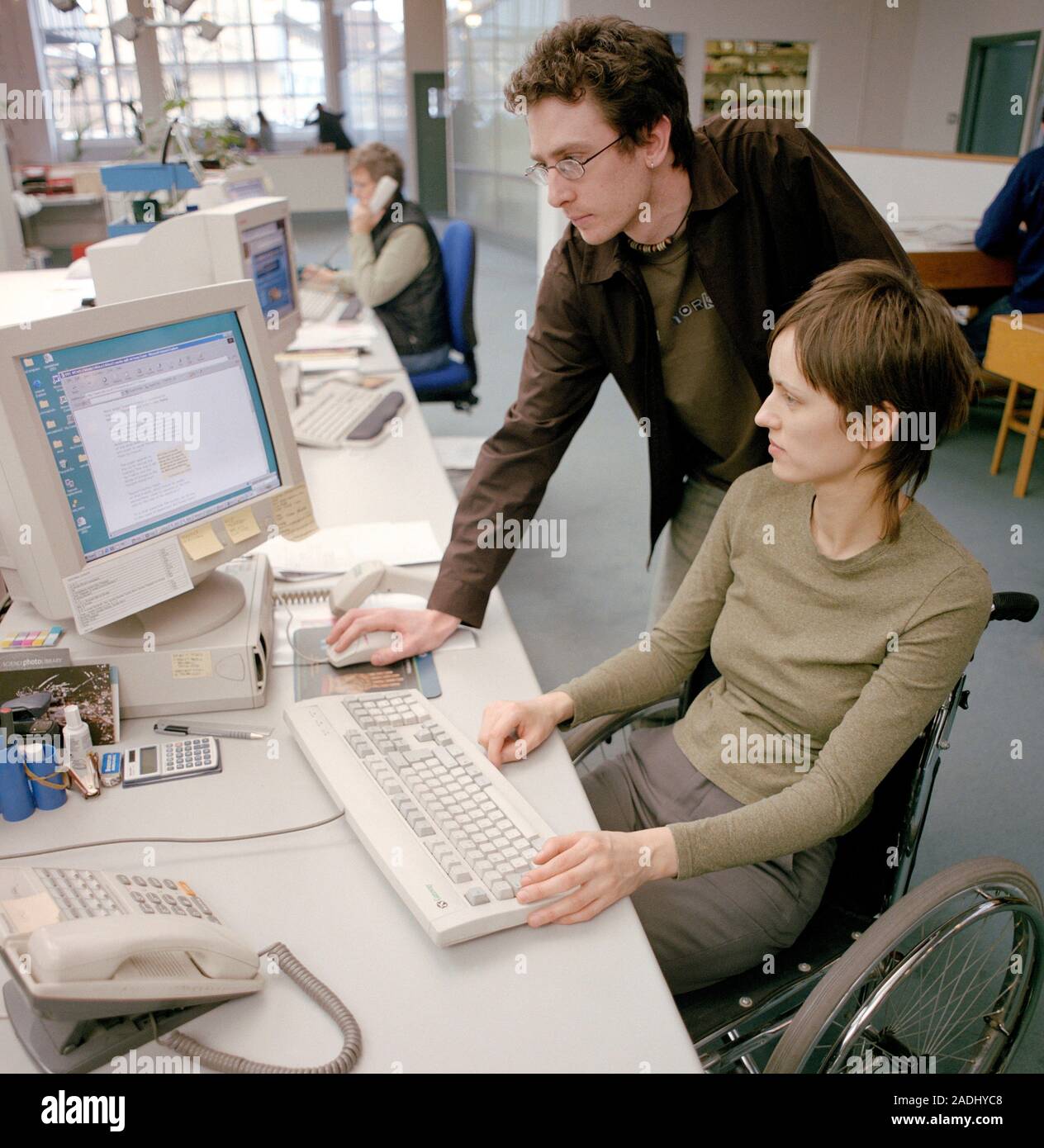 Disabled woman at work in an office with a male colleague Stock Photo ...