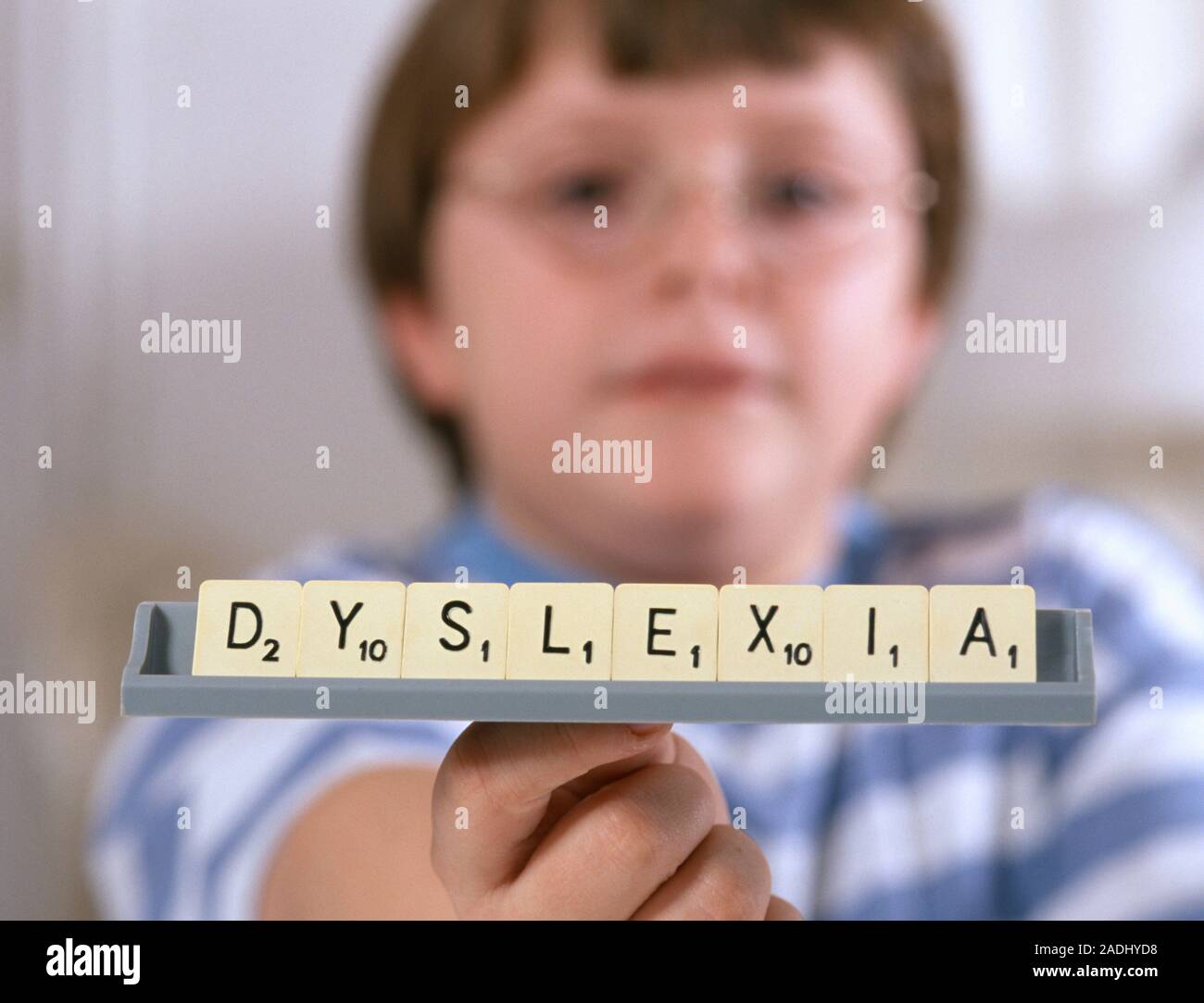 Dyslexia. Boy holding up Scrabble letters spelling the word dyslexia ...