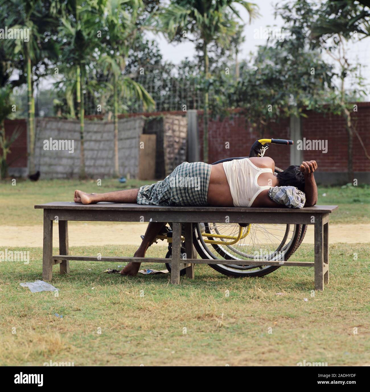 Disability. Wheelchair user resting on a bench. This man has suffered a ...