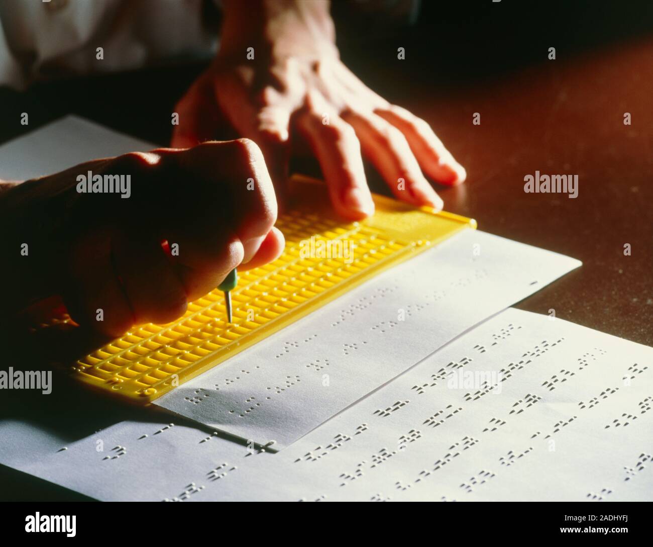 Braille. Hands use a plastic marker and a stylus to write braille on a ...