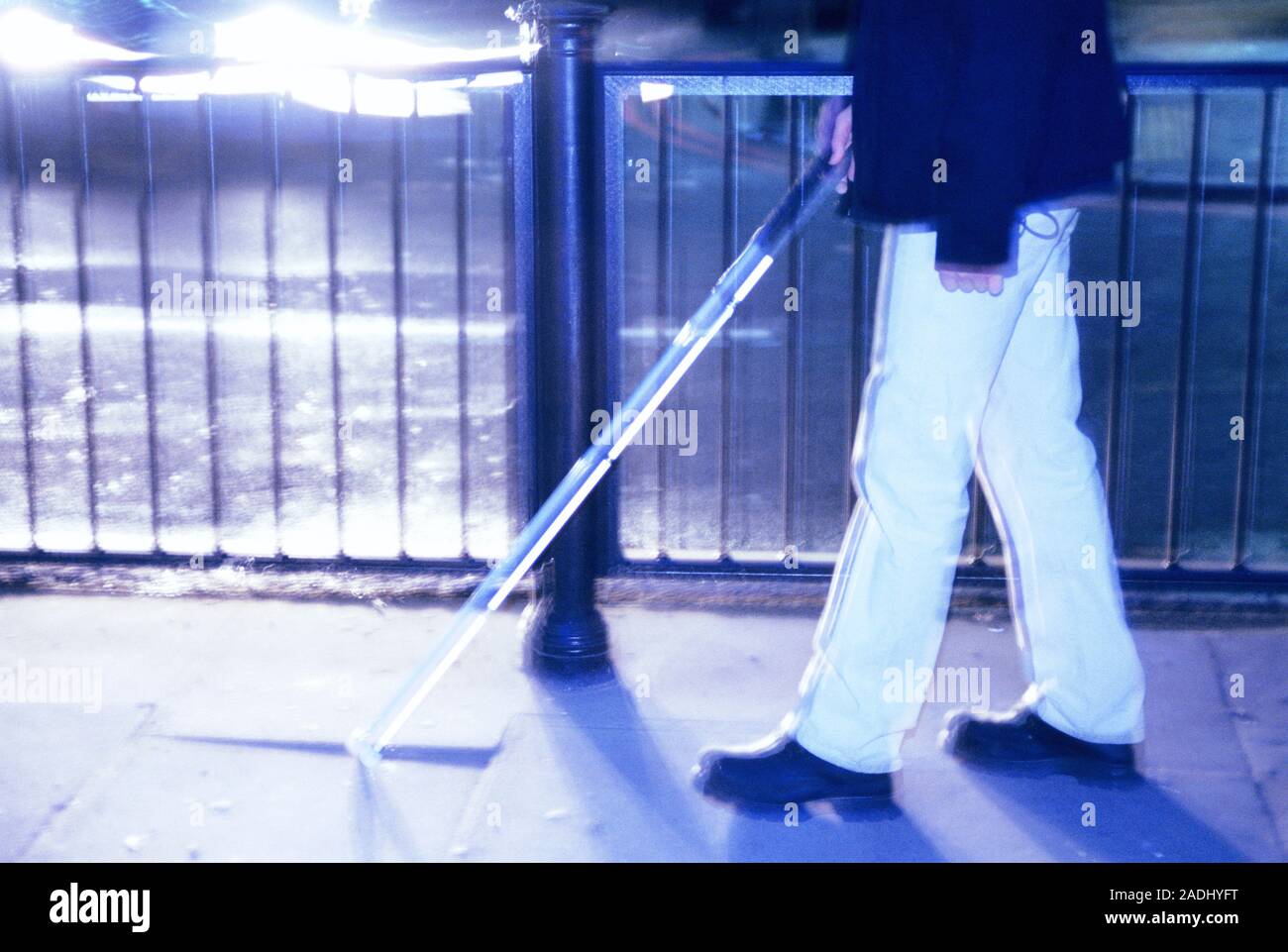 Blind man walking, with the aid of a white cane (stick). A loose paving ...