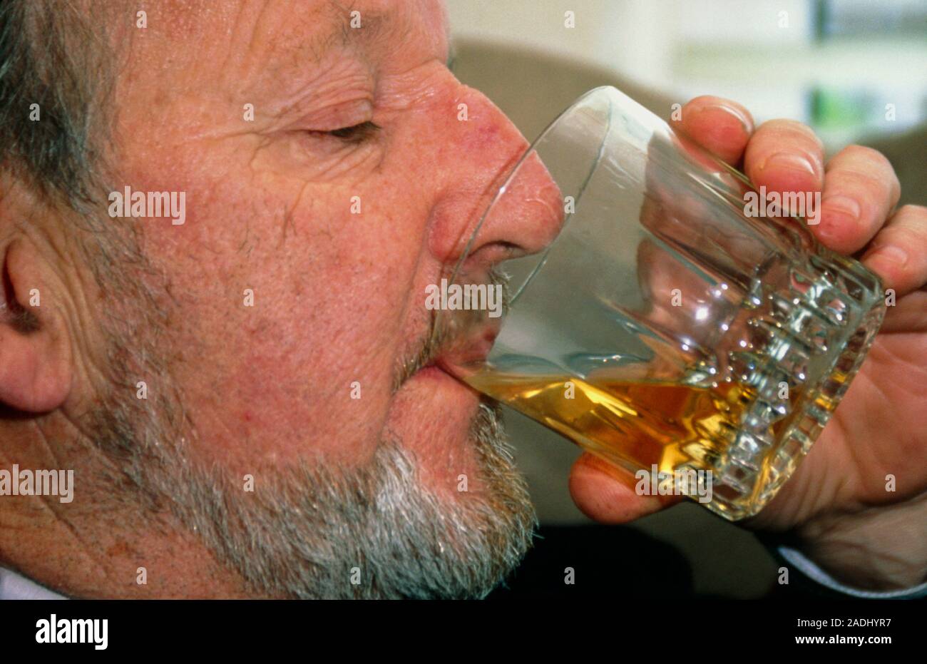 Alcohol consumption. Profile of an elderly man drinking a glass of ...