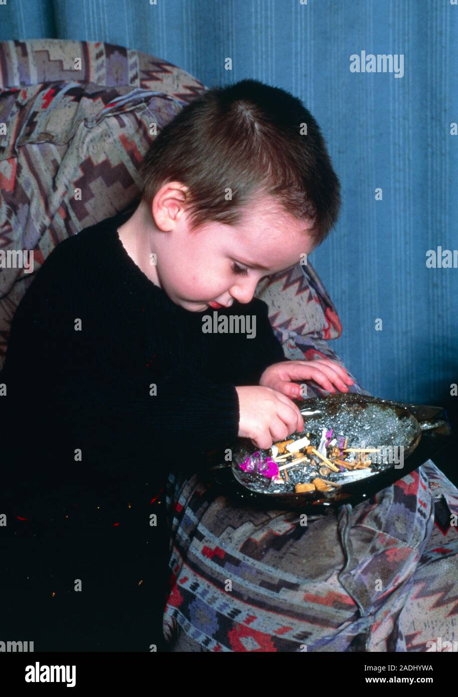 Boy with ashtray. Young boy playing with a full ashtray. Living with ...