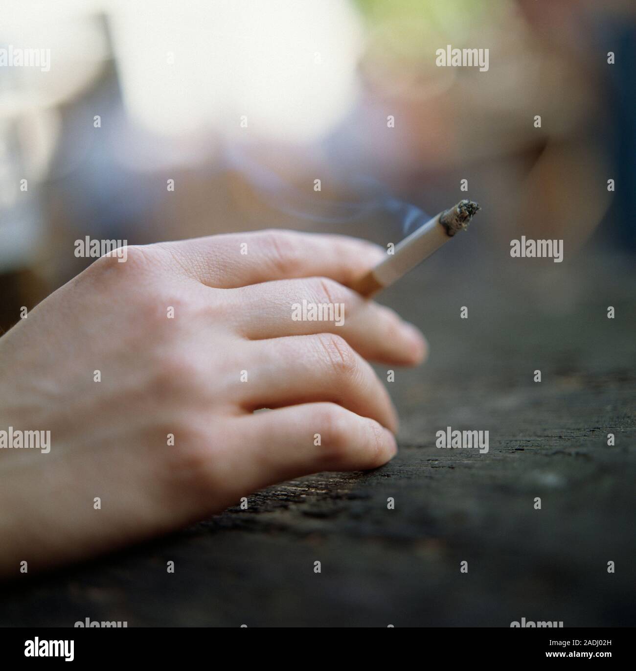 Burning cigarette held between two fingers. Cigarettes contain cancer ...