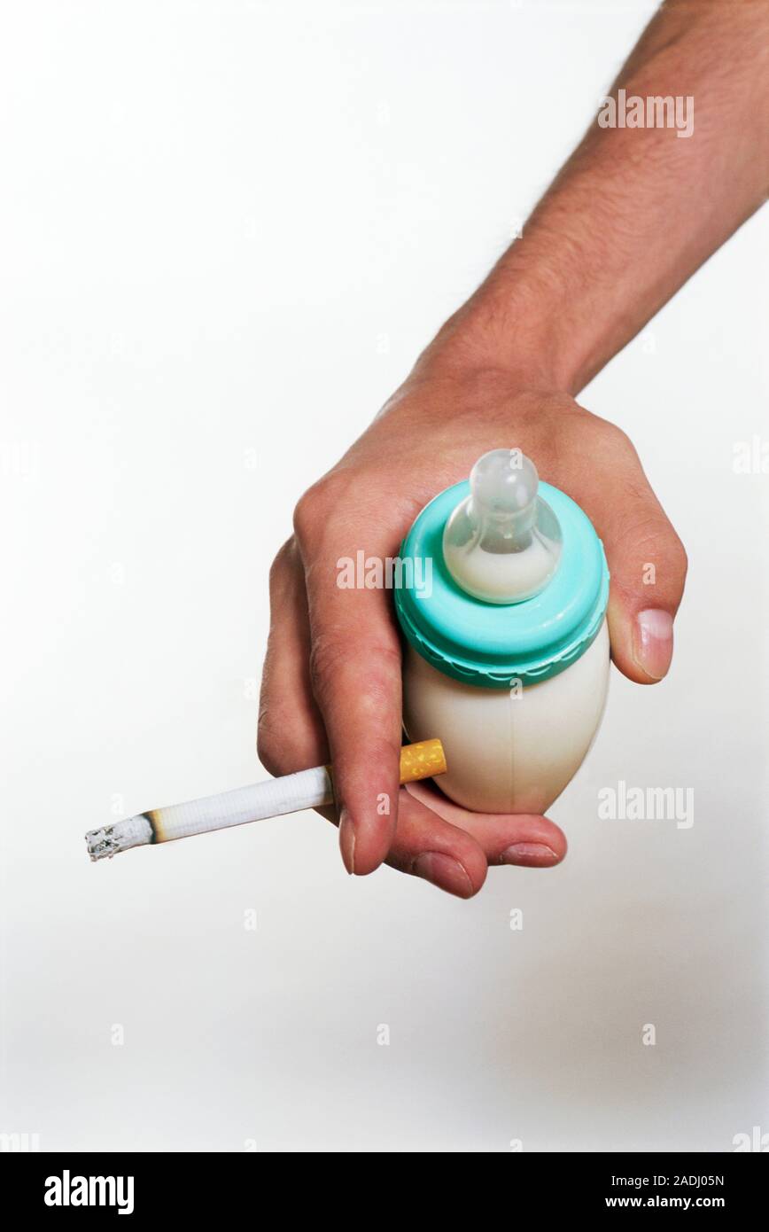 Passive smoking. Hand holding a lit cigarette and a baby's bottle ...