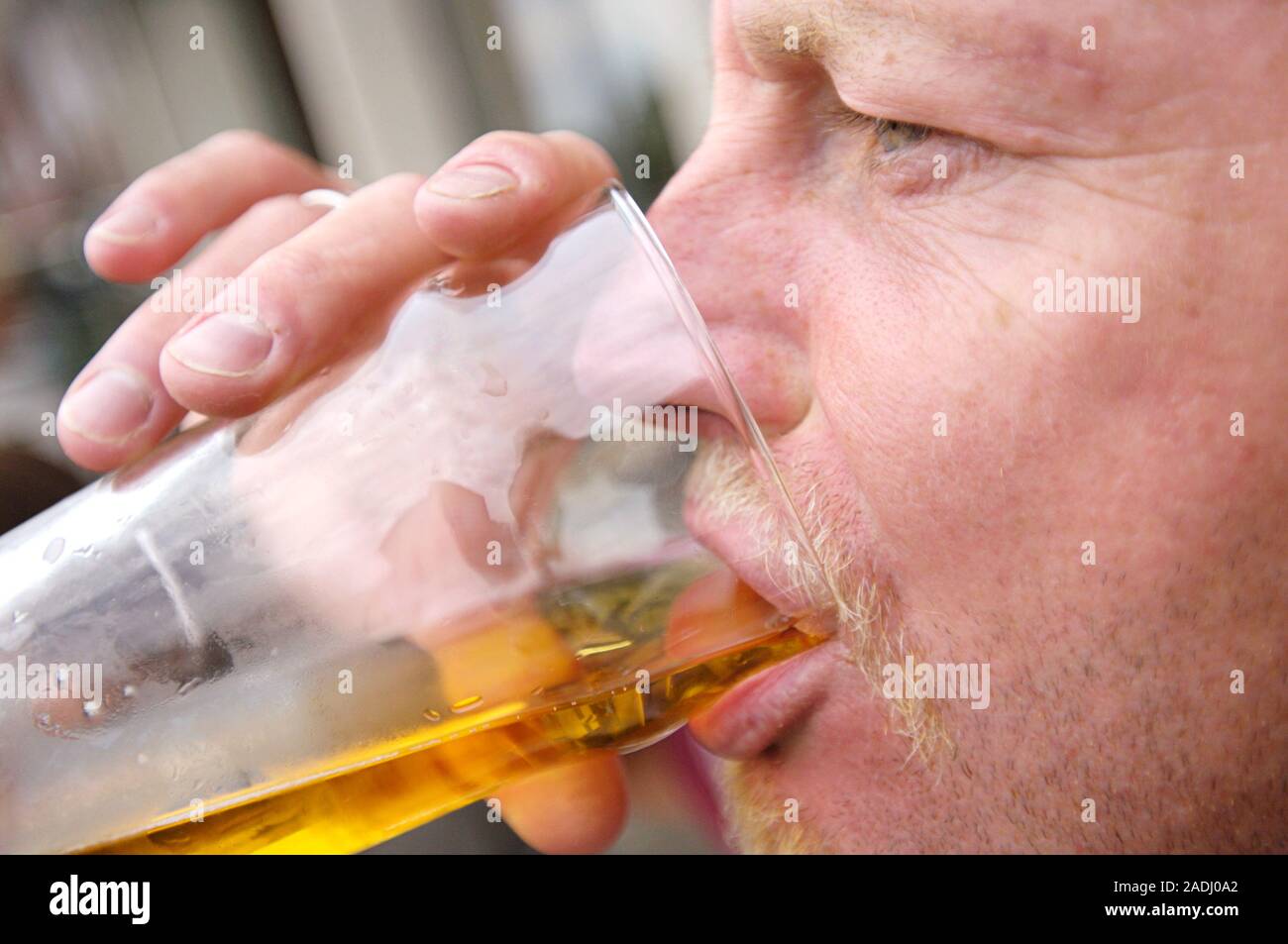Drinking alcohol. Man drinking an alcoholic drink in an outside area at ...